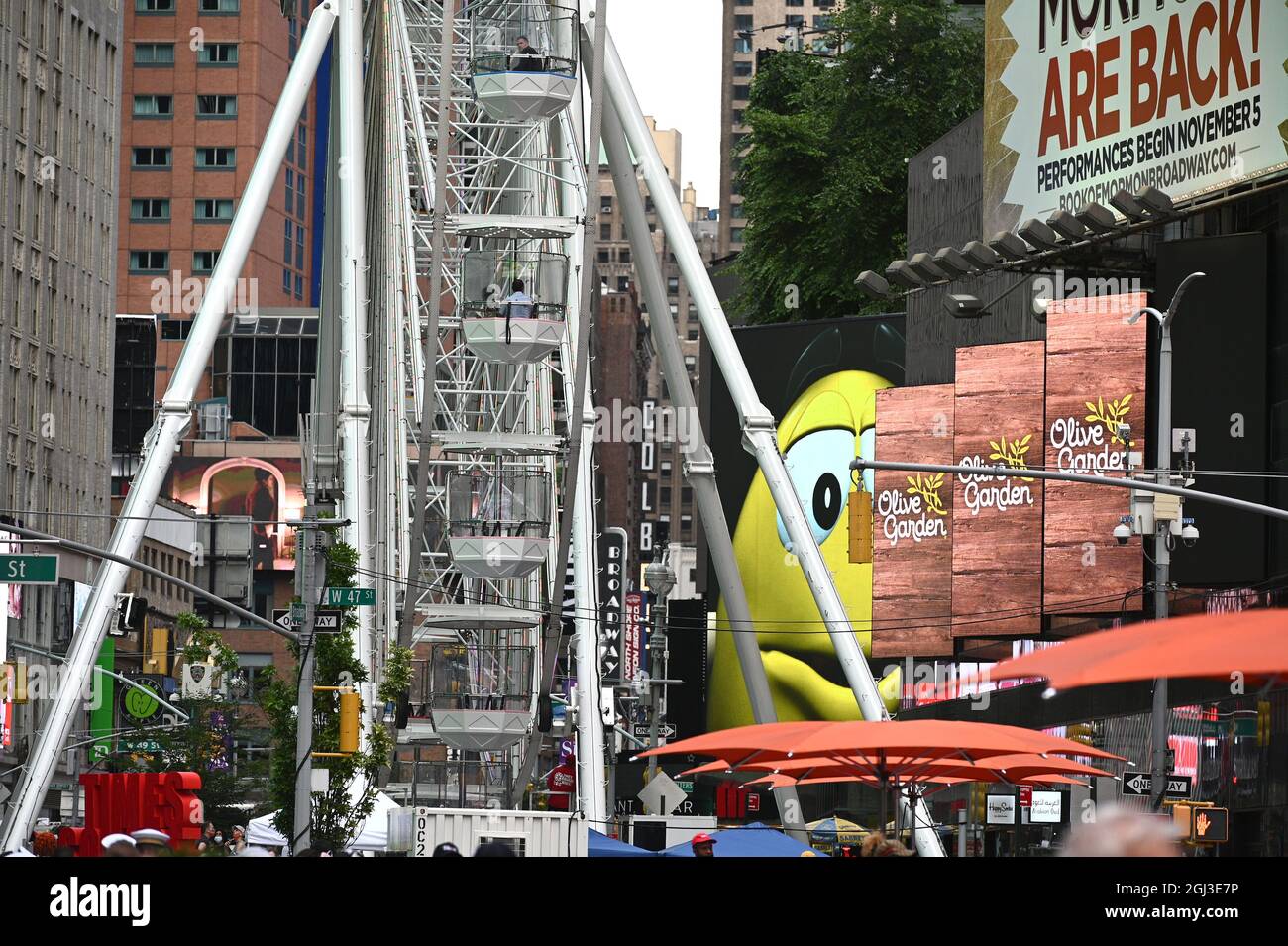 People are seen riding a ferris wheel setup along Broadway in Times ...