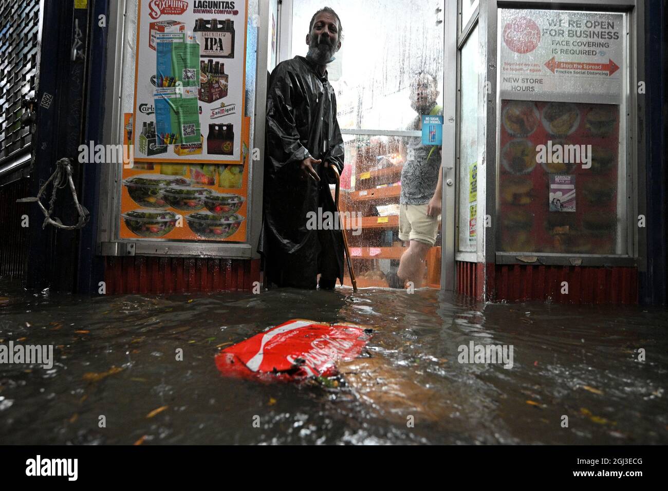 A homeless man stands in the doorway of a deli during flash flooding ...
