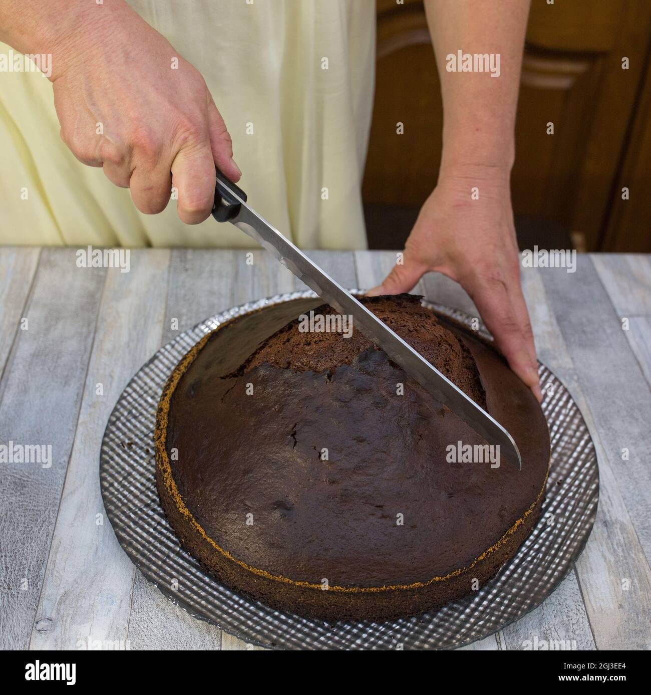 Cake making process. A woman cuts a baked chocolate cake into slices ...