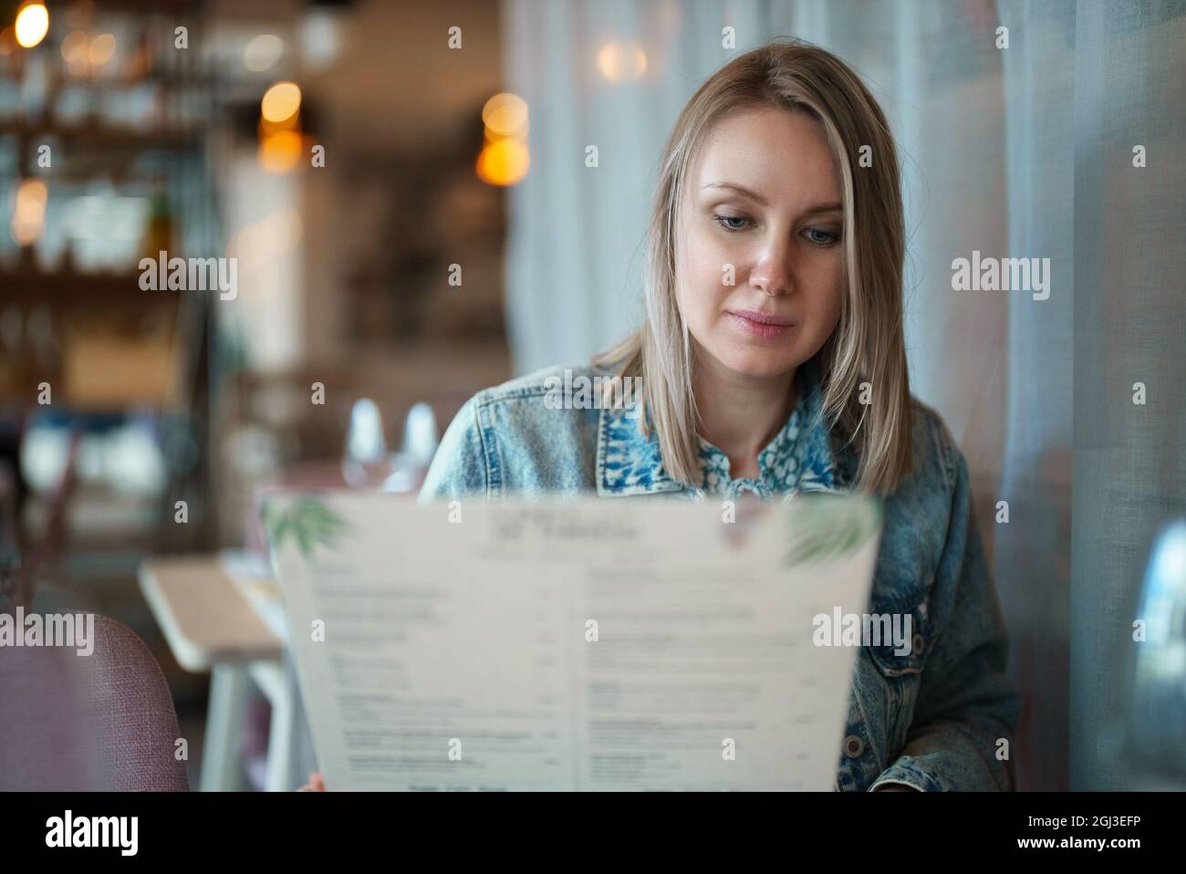 Woman is looking at menu in restaurant Stock Photo - Alamy