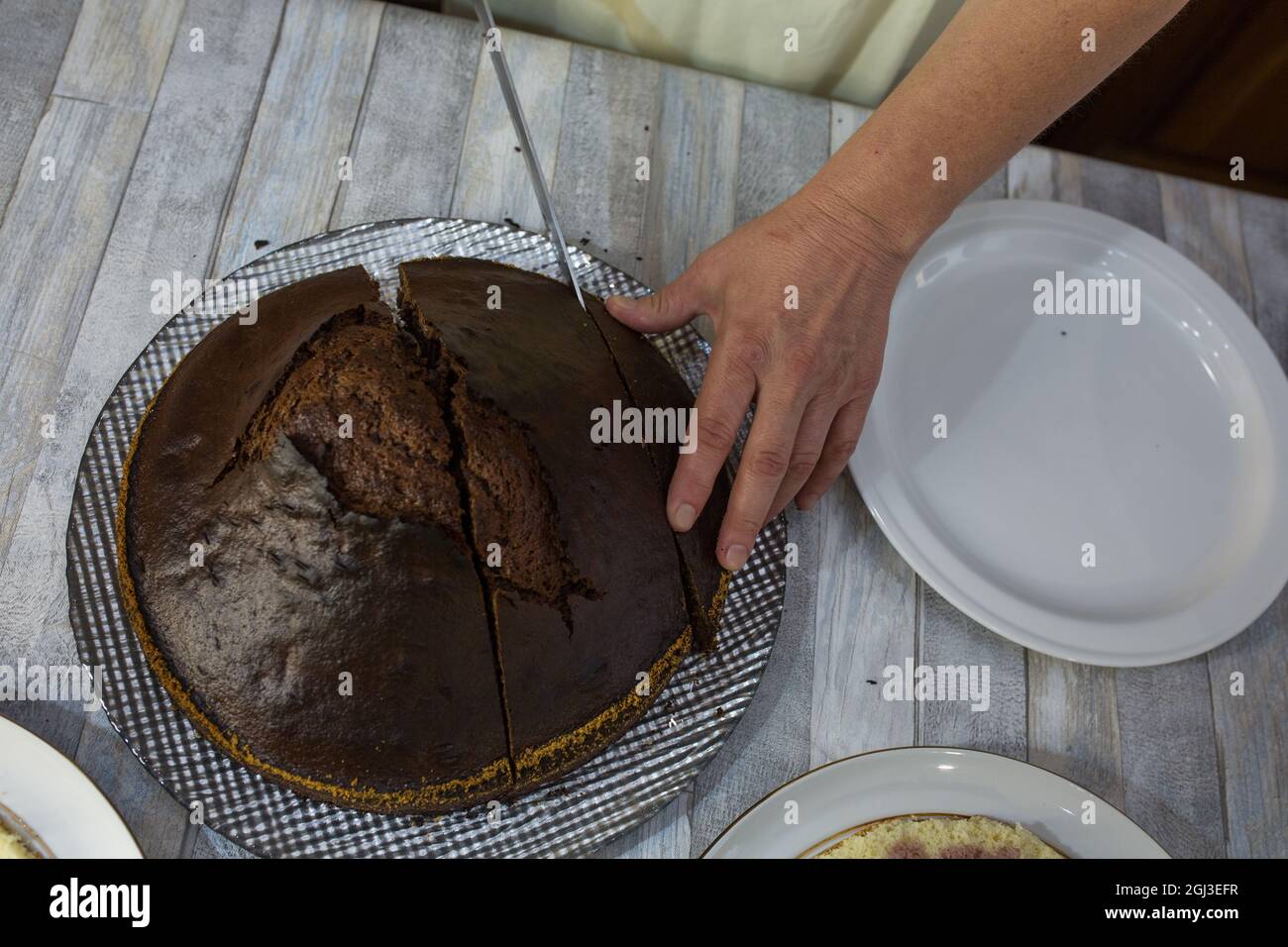 Cake making process. A woman cuts a baked chocolate cake into slices ...