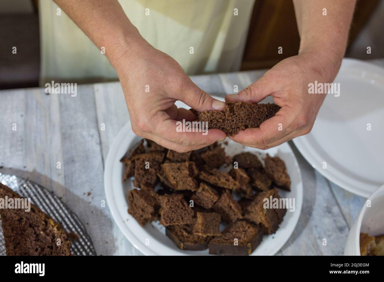 Cake making process. A woman cuts a baked chocolate cake into slices ...