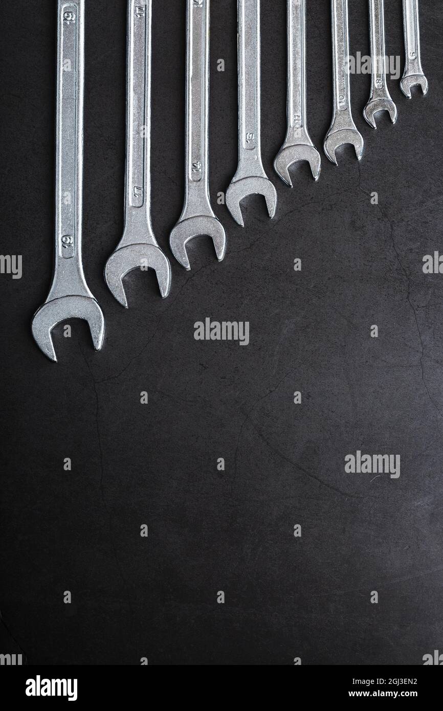 A set of wrenches on a textured black background in a row. Top view ...