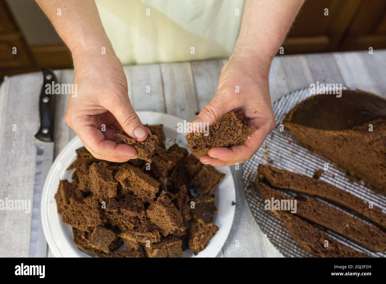 Cake making process. A woman cuts a baked chocolate cake into slices ...