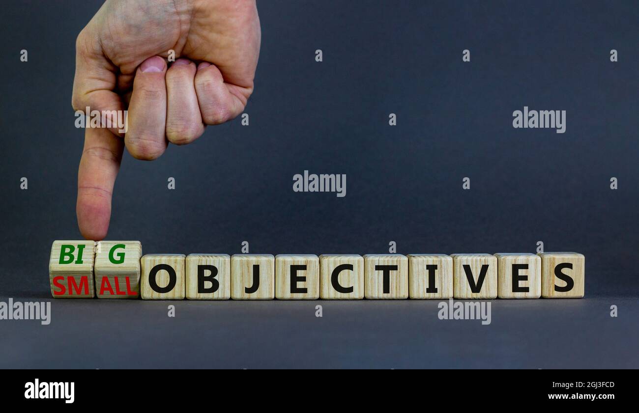 Big or small objectives symbol. Businessman turns wooden cubes, changes ...