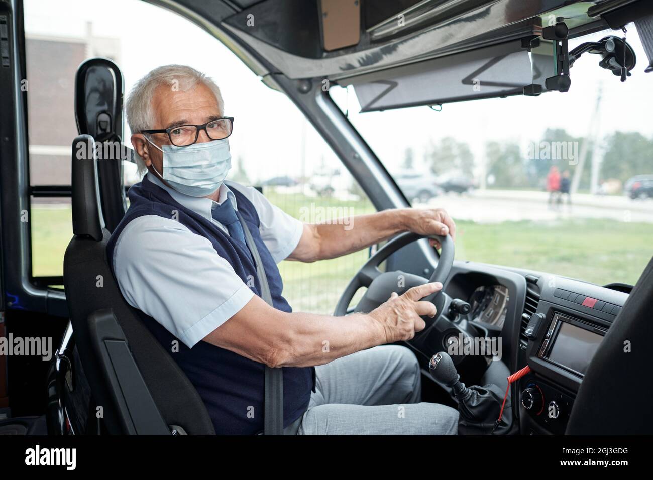 Portrait of senior white-haired bus driver in eyeglasses and facial ...