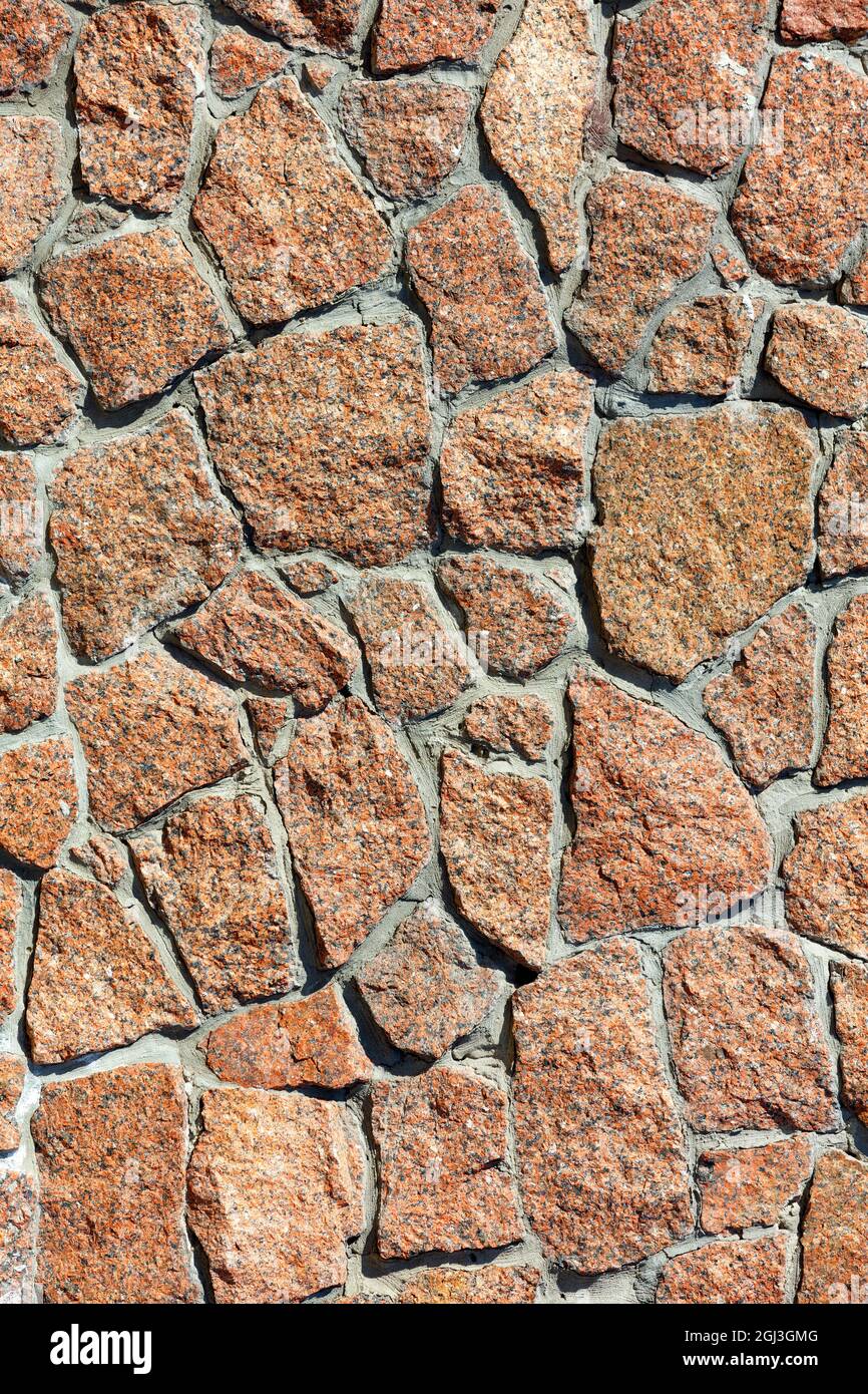 The texture of the red granite wall and the background of large stones ...