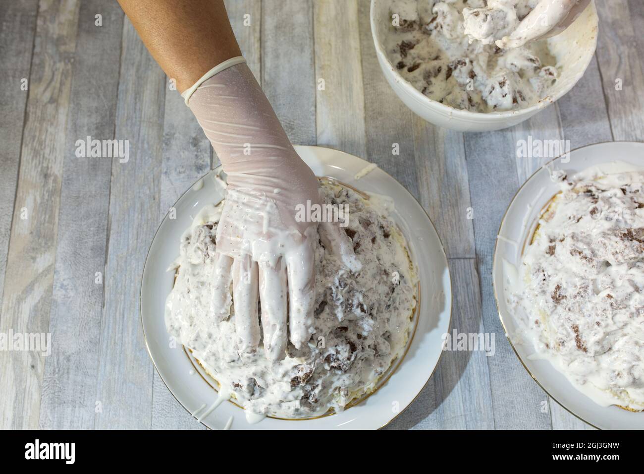 Cake making process. Female hands in culinary gloves form a chocolate ...
