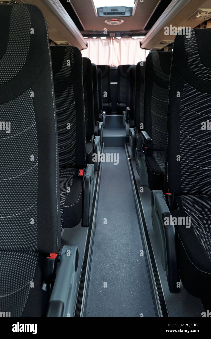 Interior of empty clean bus aisle with rows of black cloth seats Stock ...