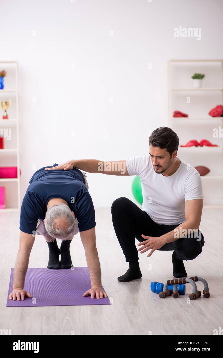 Young instructor and old man doing sport exercises Stock Photo - Alamy