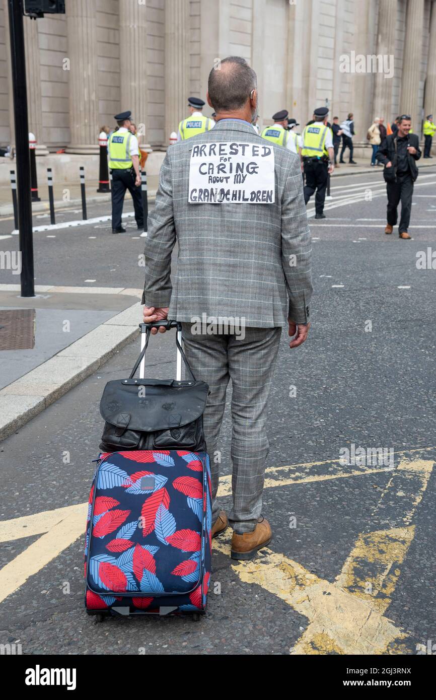 A protester wears a sign saying Arrested for caring about my ...