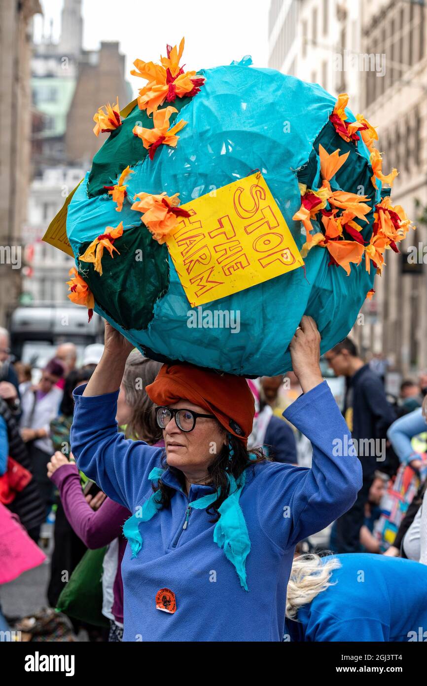 A protester carrying an earth object on her head which says "Stop the ...