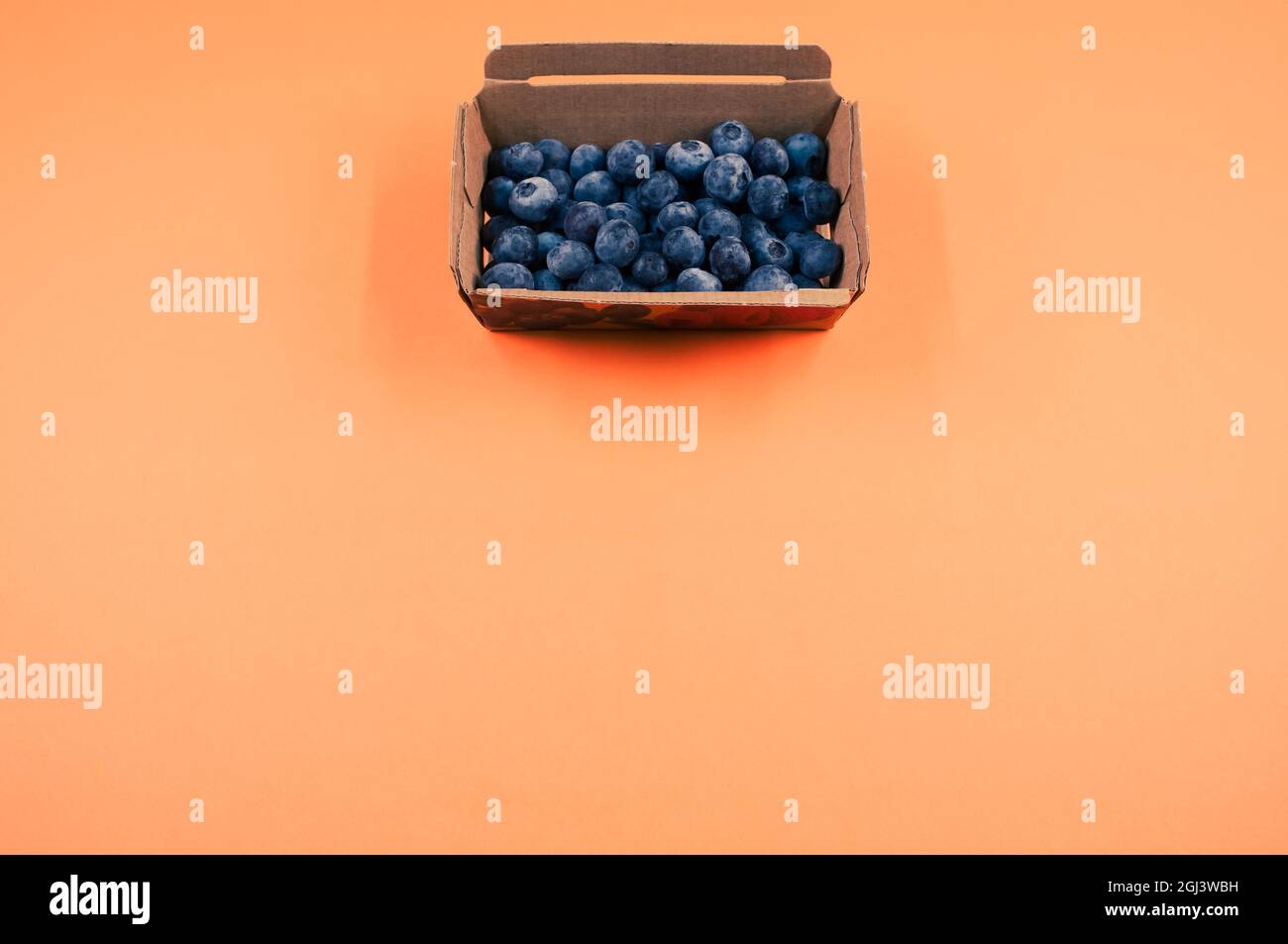 Top view fresh blueberry inside a paper box isolated on orange ...