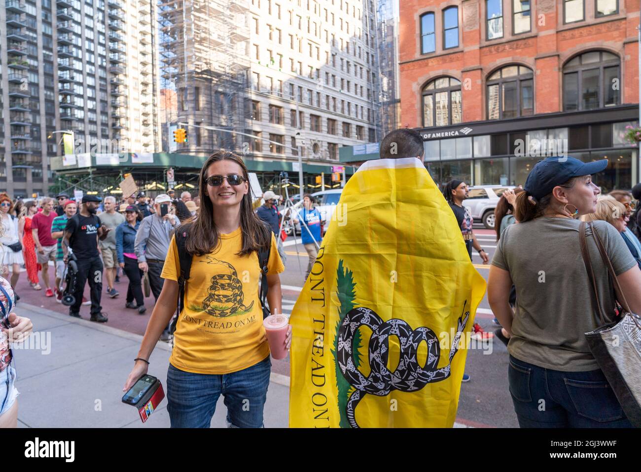 Pedestrians adorn with the Gadsden flag watch as anti-vaccination ...