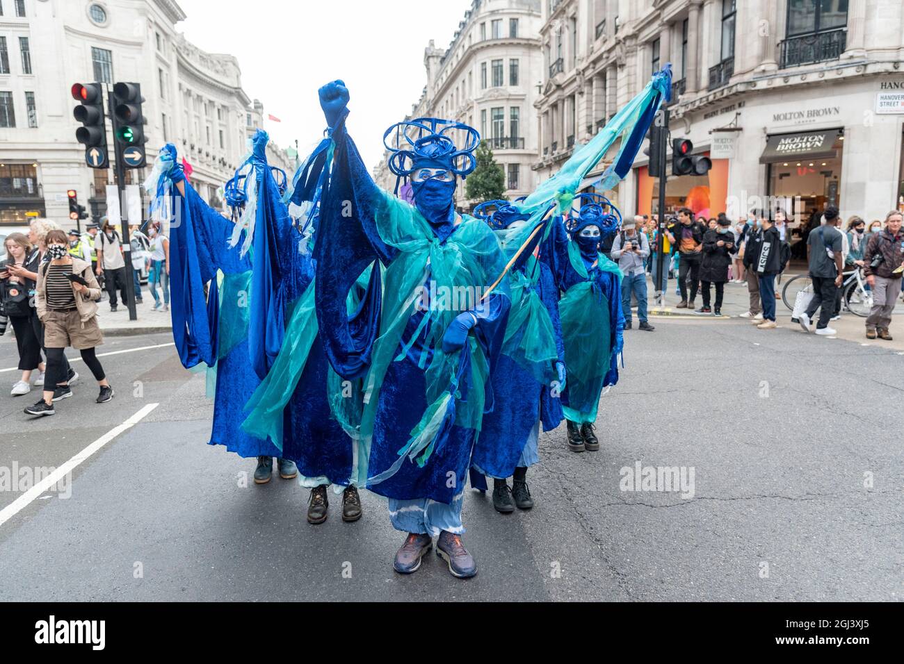 Protesters in blue with painted white faces perform a wave movement to ...