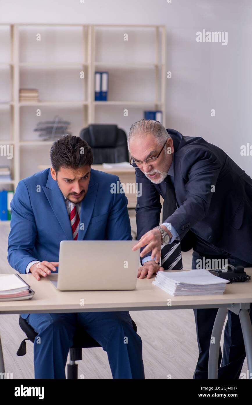 Old boss and young employee in bullying concept Stock Photo - Alamy