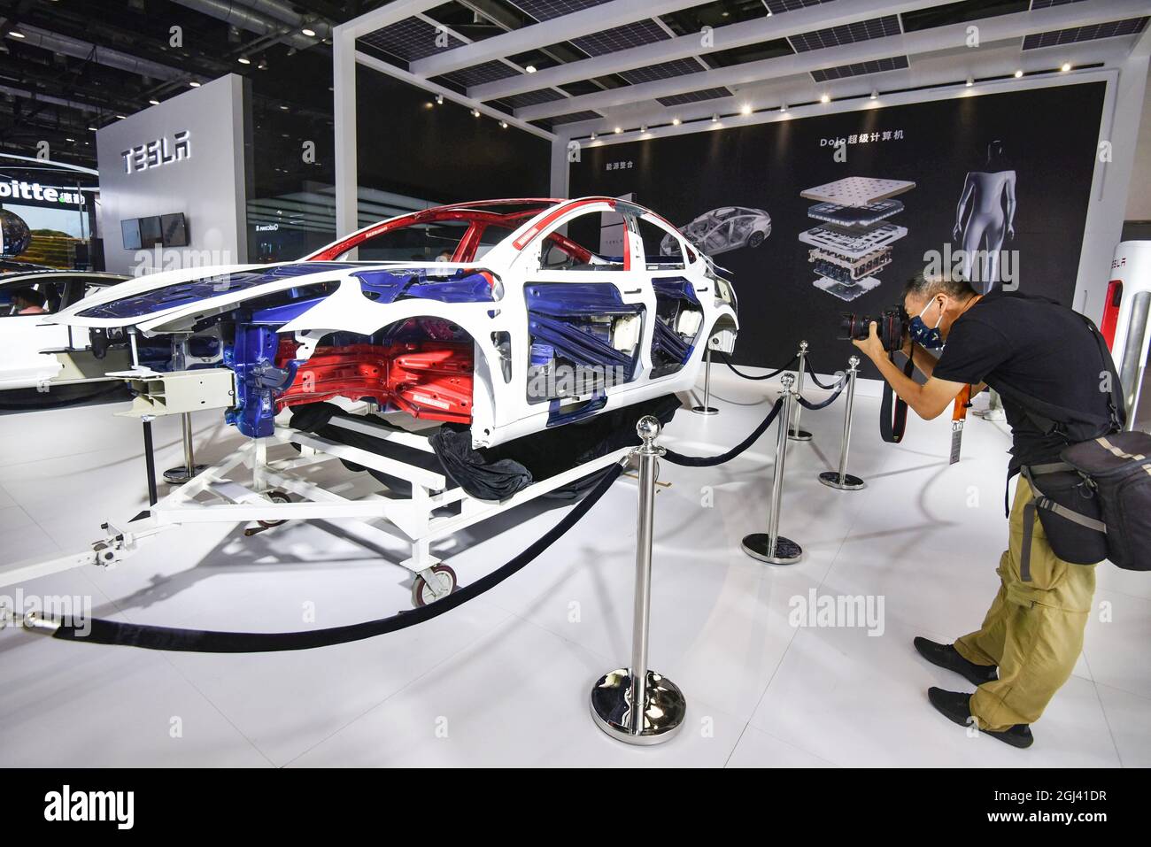In the Tesla showroom, a man taking pictures of the skeleton of a Tesla ...