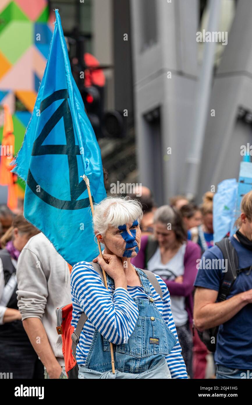 A protester with her face painted, holds an XR flag, during Extinction ...