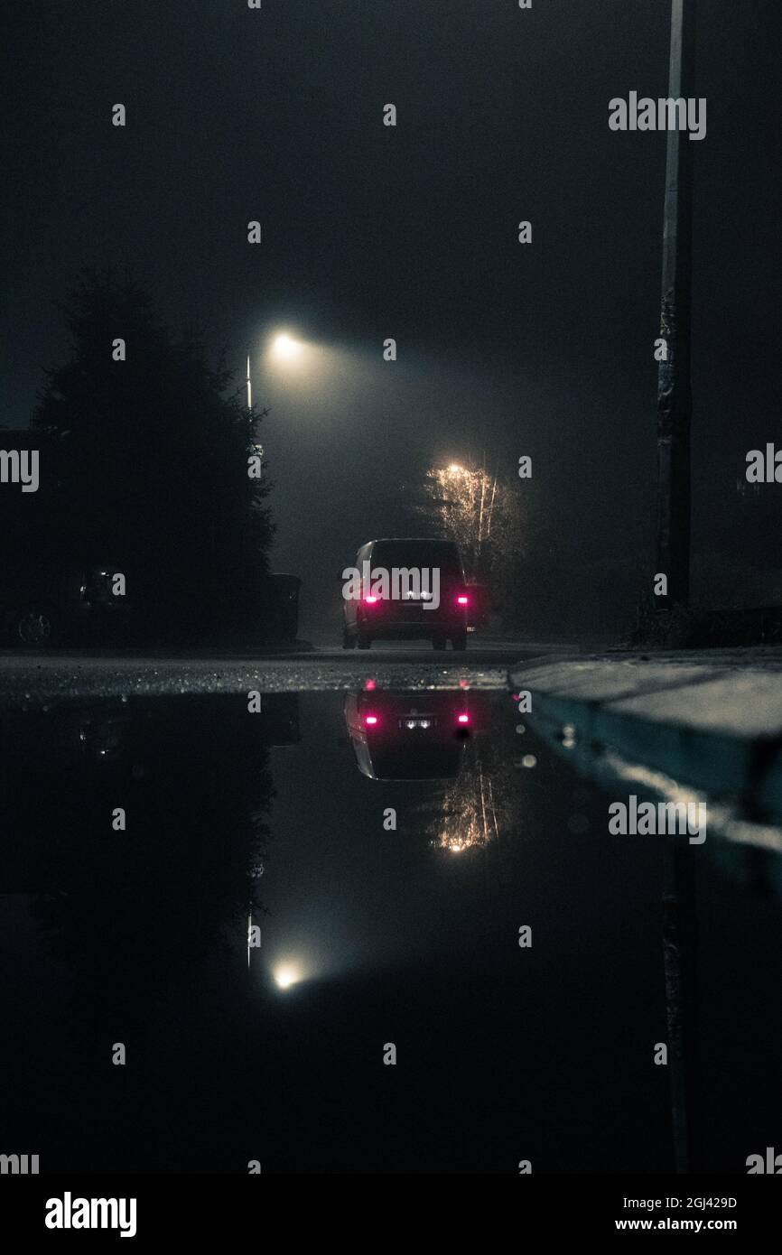 A van on a dark foggy street with a reflection in water at night Stock ...