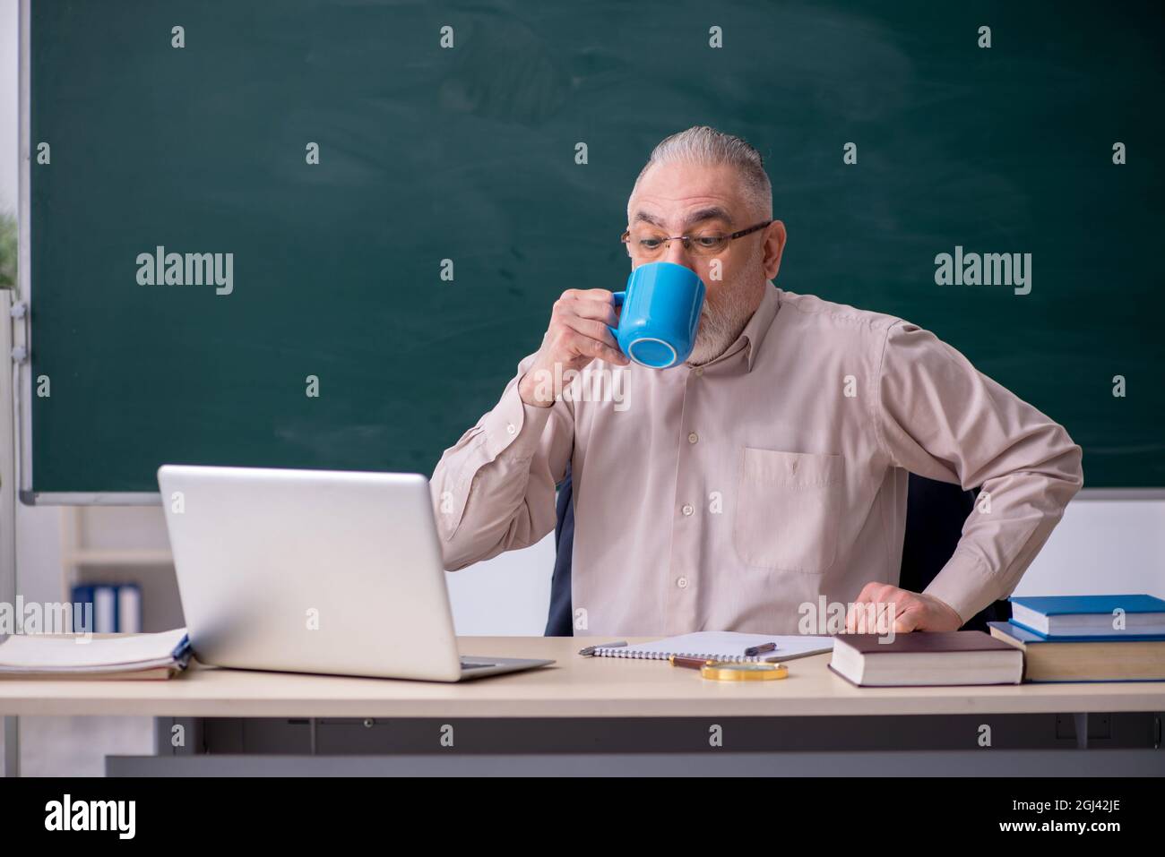 Old teacher drinking coffee in the classroom Stock Photo - Alamy