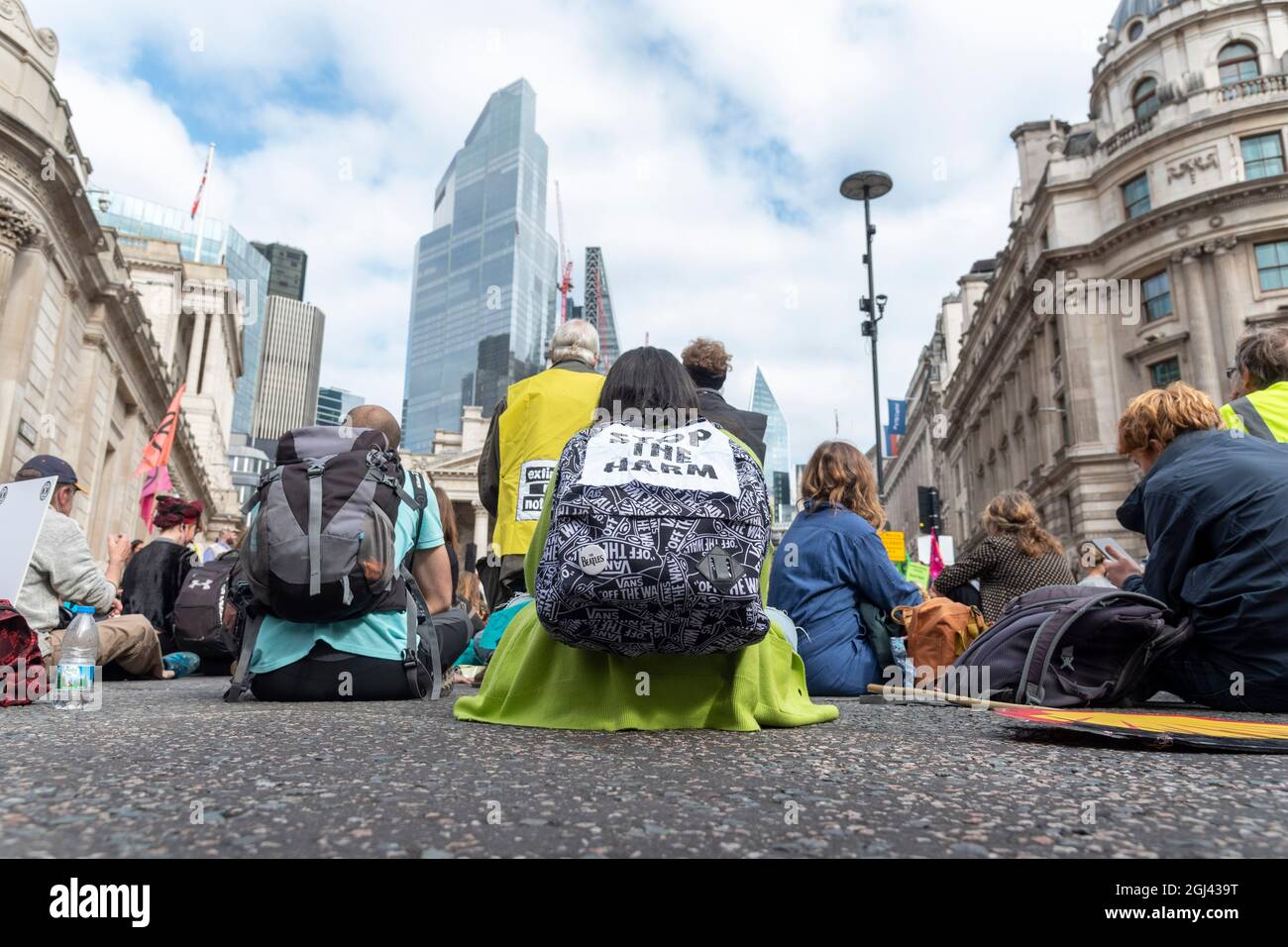 A protester with Stop the harm on her bag sits on the road during the ...