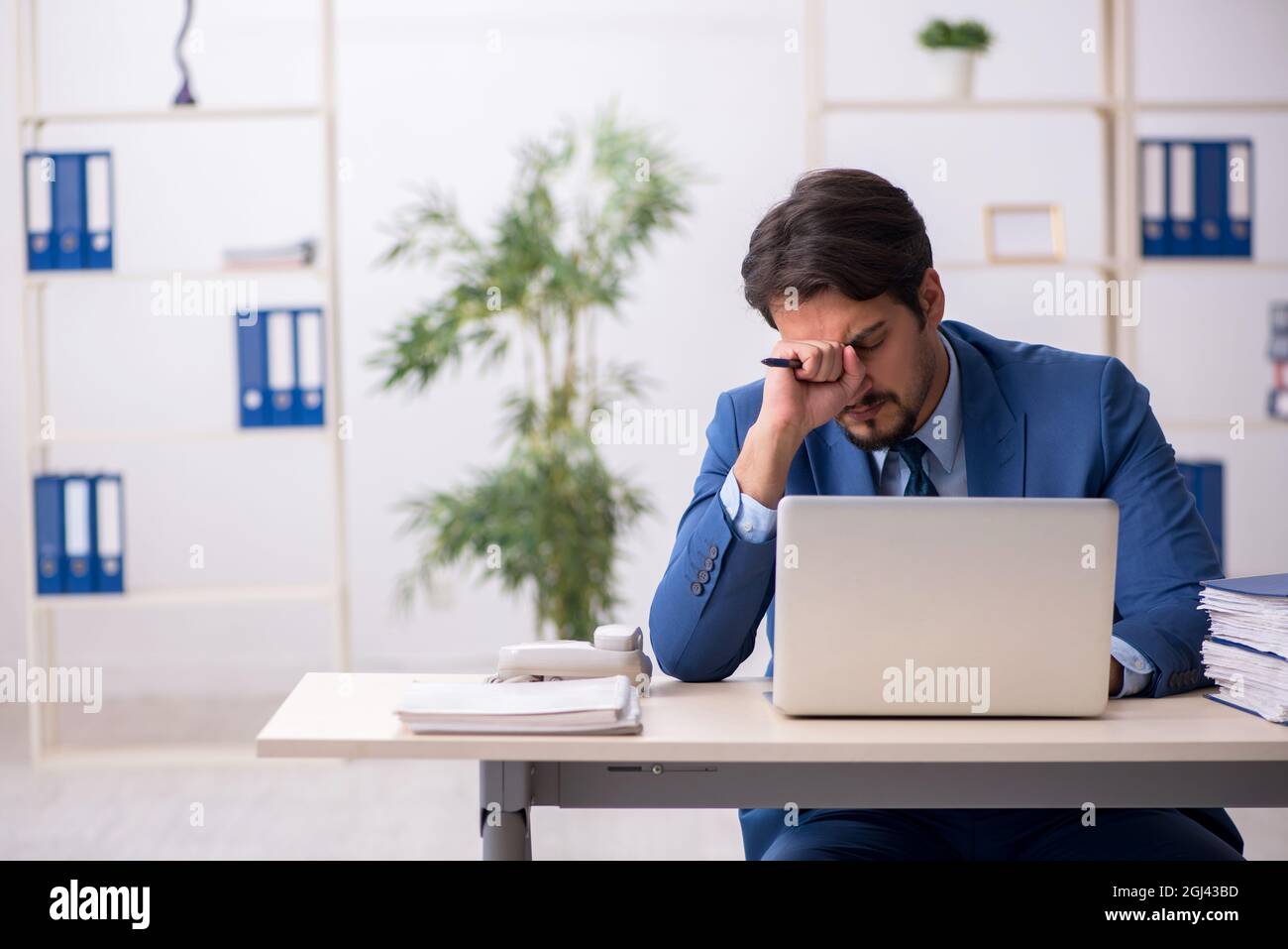 Young employee and too much work in the office Stock Photo - Alamy