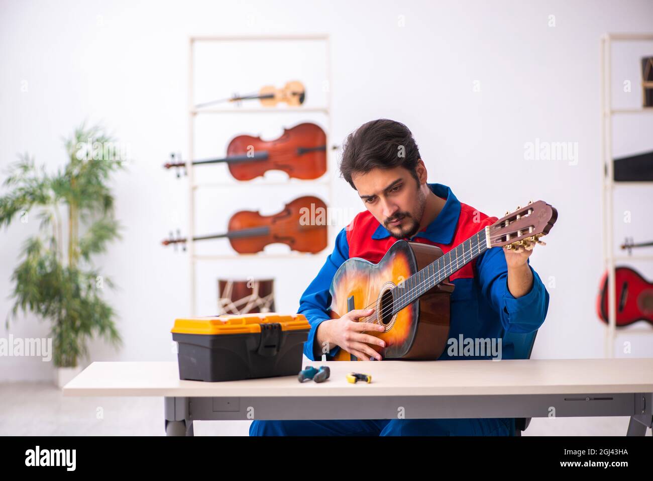 Young repairman repairing musical instruments at workplace Stock Photo ...