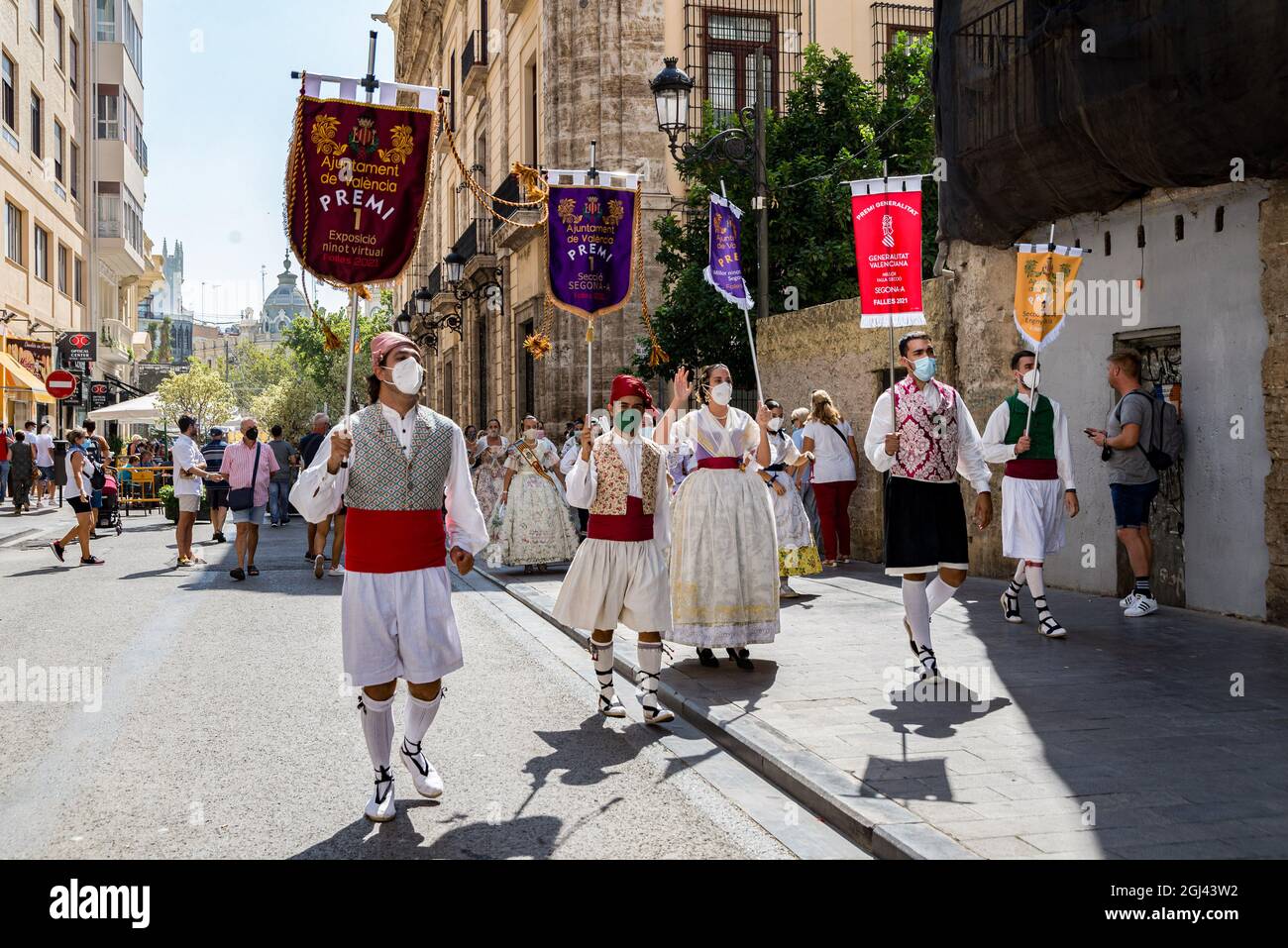 Falleros wearing masks carry the awards flags during a parade in ...