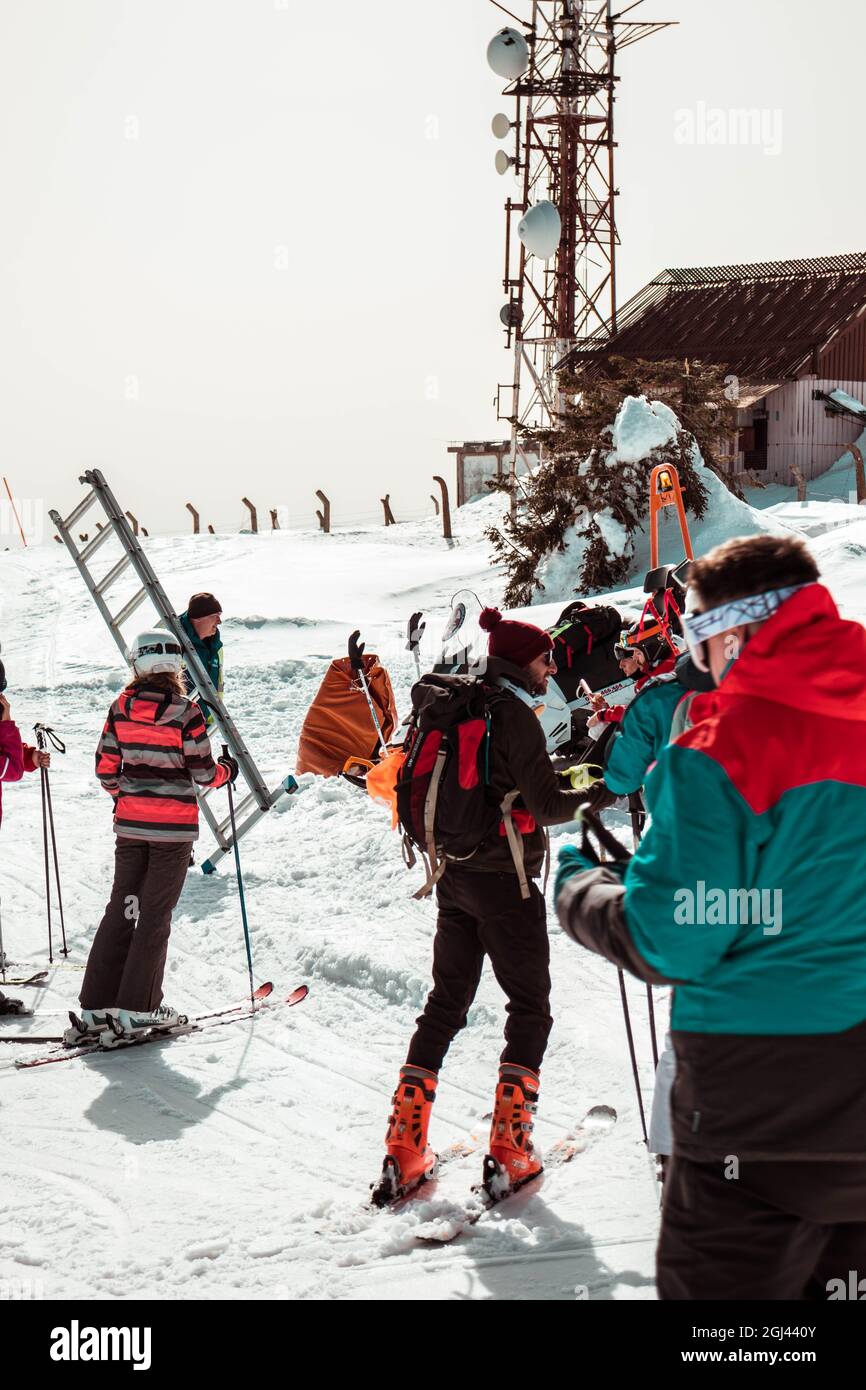 Skiers on the top of the slope and ski control with ladders in hand ...