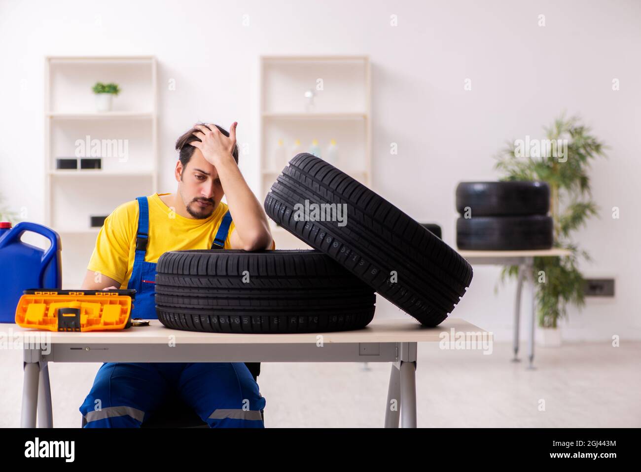 Young garage worker with tyre at workshop Stock Photo - Alamy