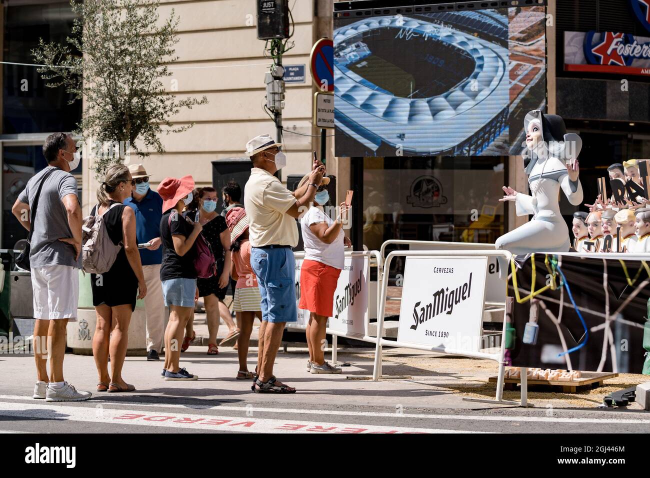People with masks take photos of a Falla in Valencia. Las Fallas, the ...