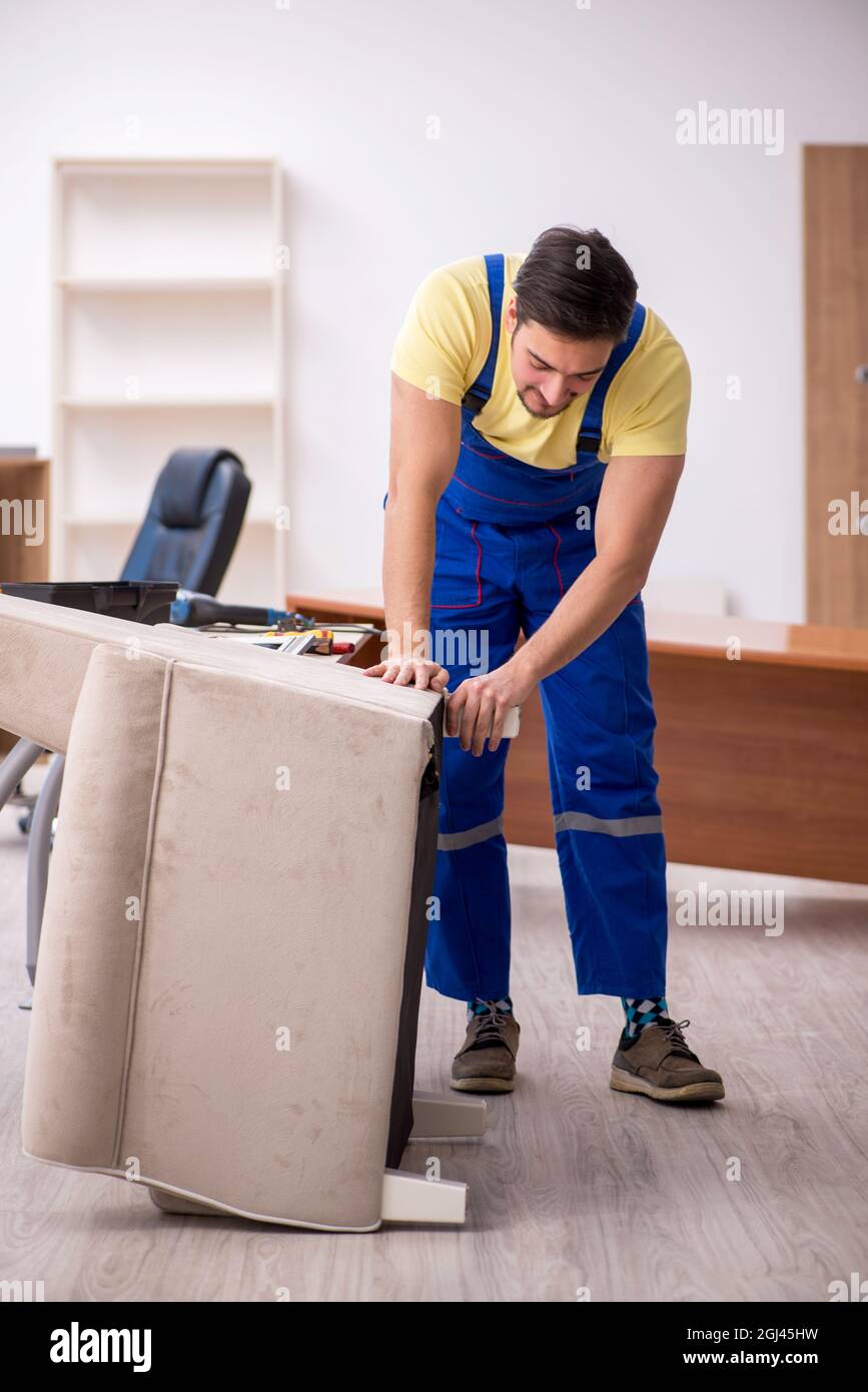 Young carpenter repairing arm-chair in the office Stock Photo - Alamy