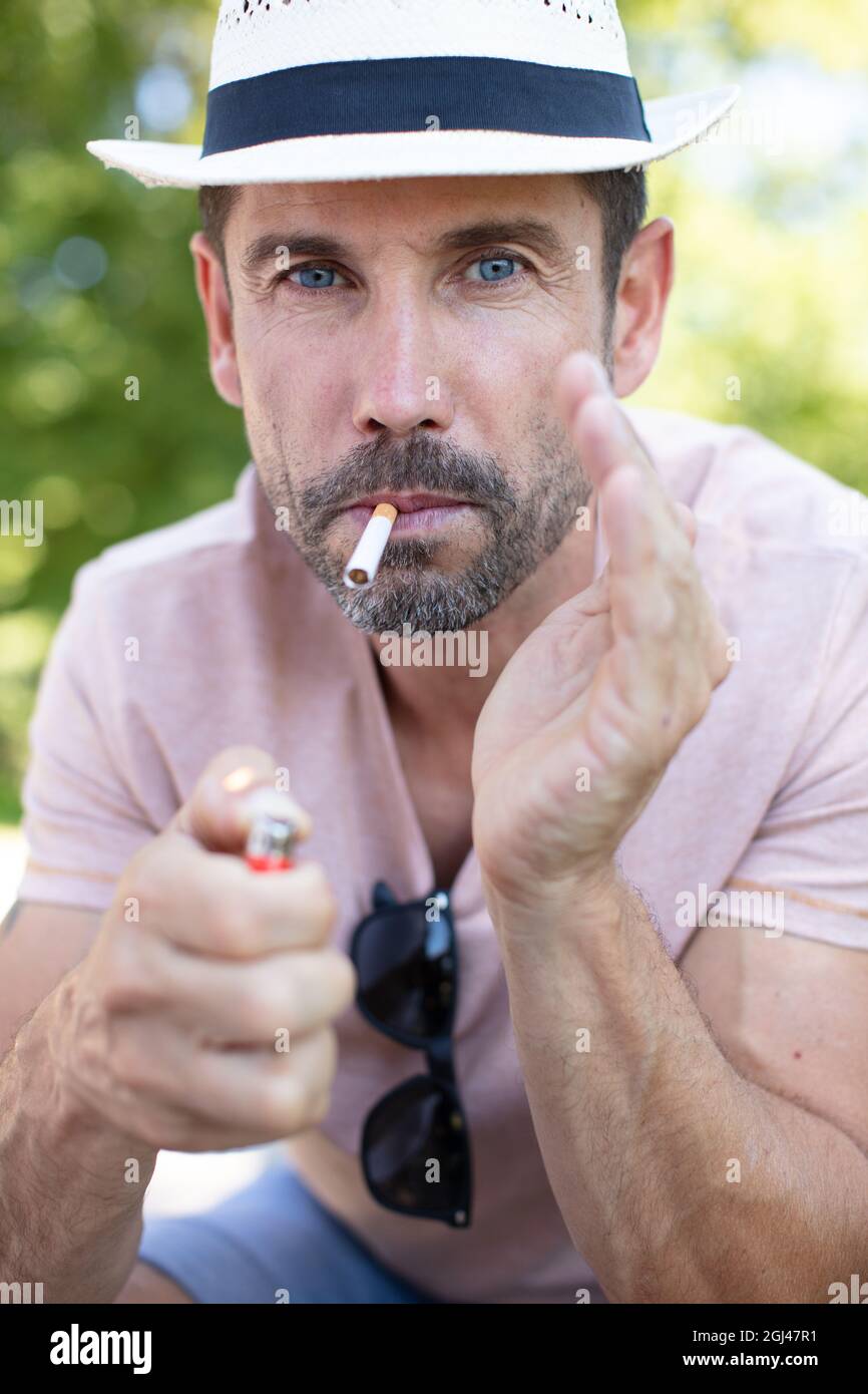 man trying to ignite the cigarette in a park Stock Photo - Alamy