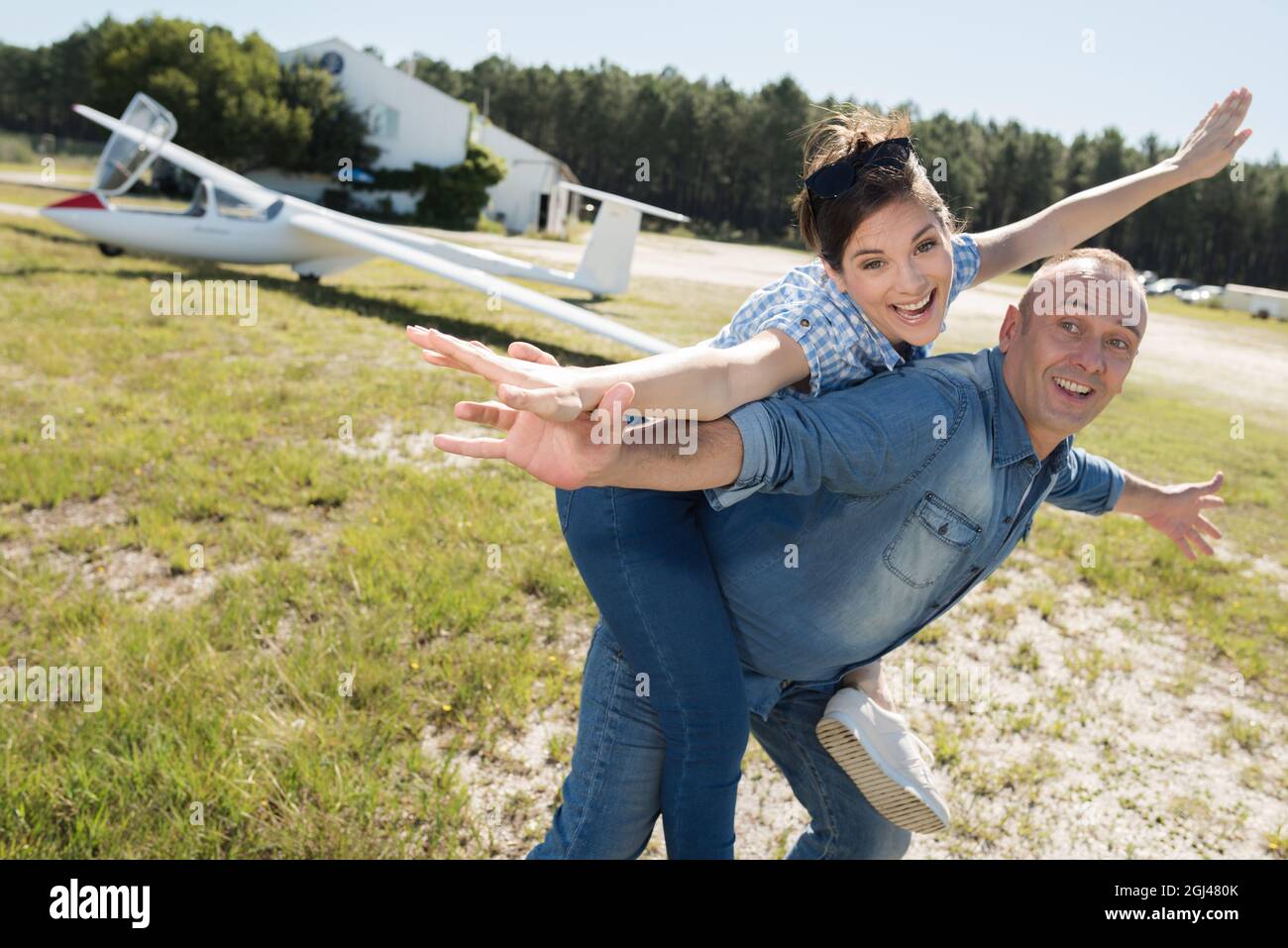 man giving his girlfriend piggyback arms outstretched like an aircraft ...