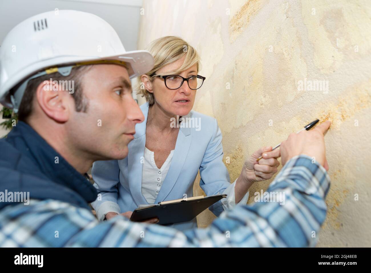 builder and suited woman inspecting wall Stock Photo - Alamy