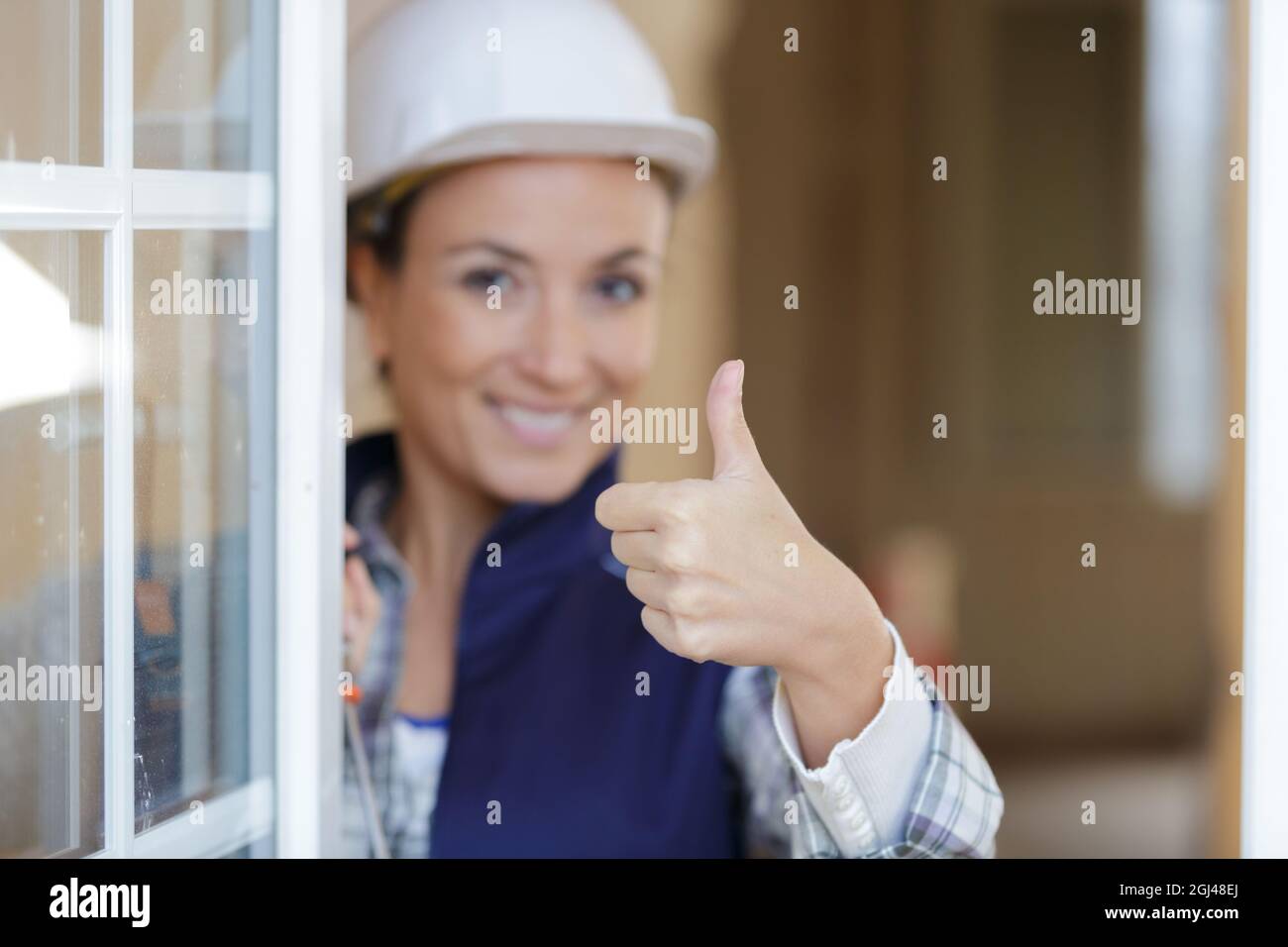 female window fitter holding thumbs up Stock Photo - Alamy