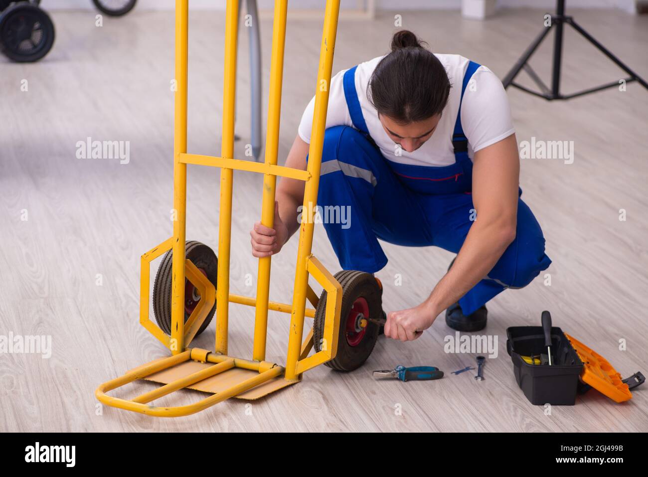 Young repairman repairing trolley indoors Stock Photo - Alamy