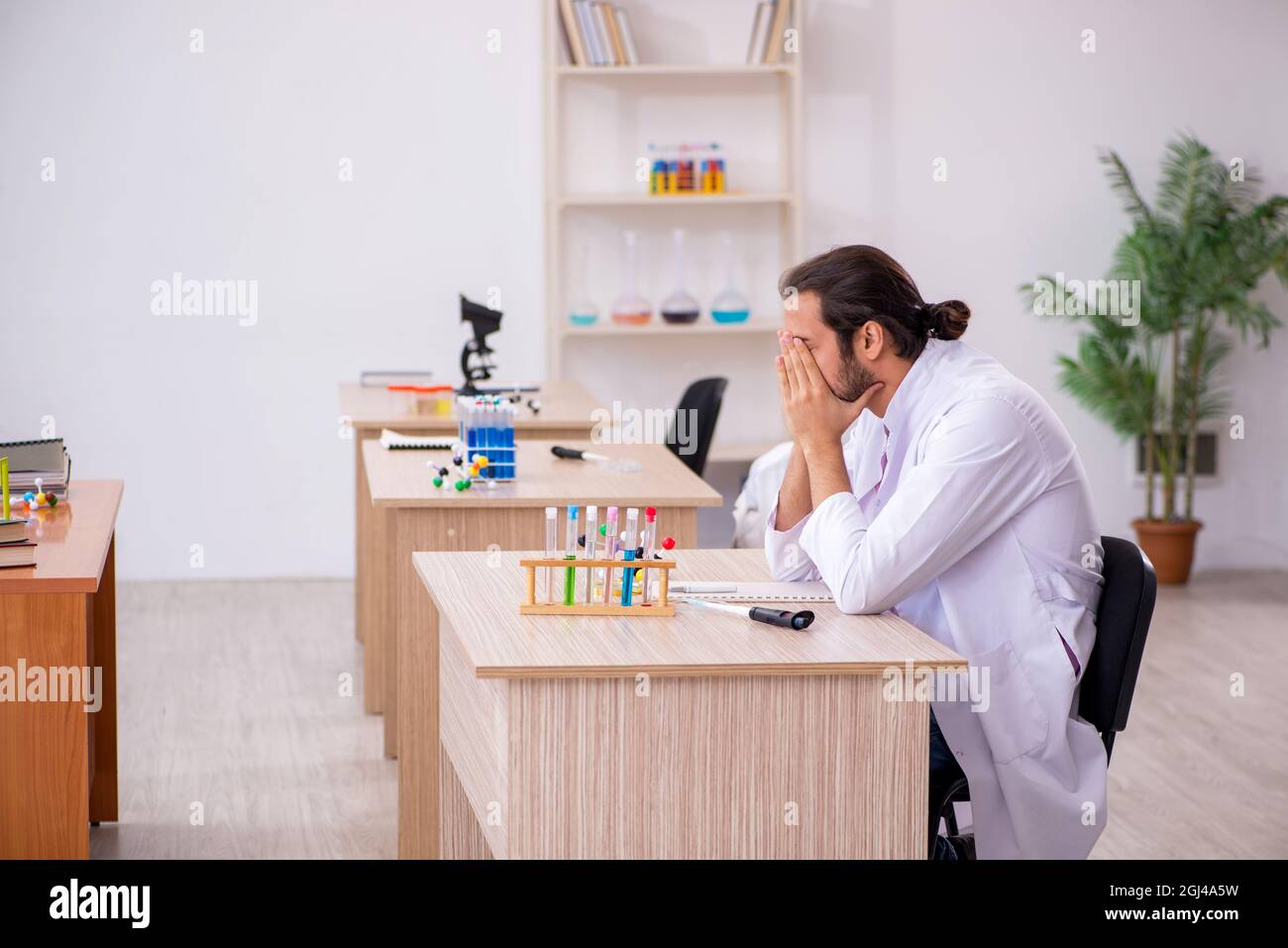 Young chemist sitting at the desk in the classroom Stock Photo - Alamy