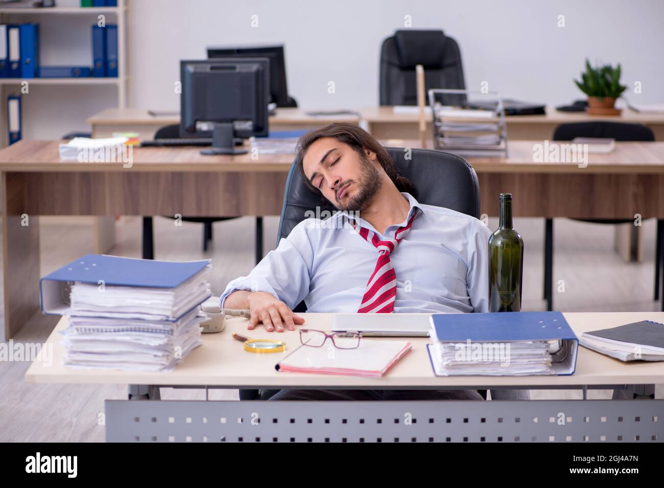 Young male employee drinking alcohol at workplace Stock Photo - Alamy