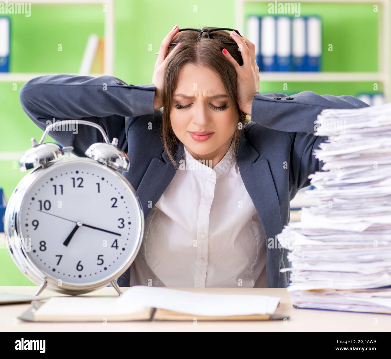 Young female employee very busy with ongoing paperwork in time ...