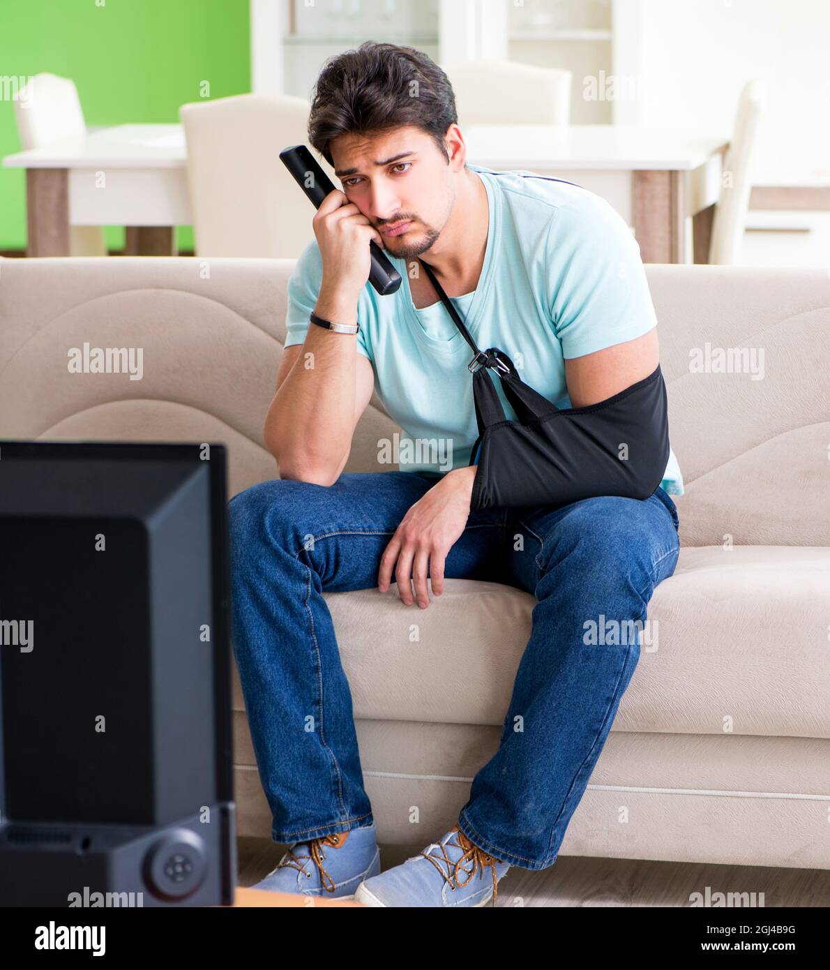 The arm injured man sitting on the sofa watching tv Stock Photo - Alamy
