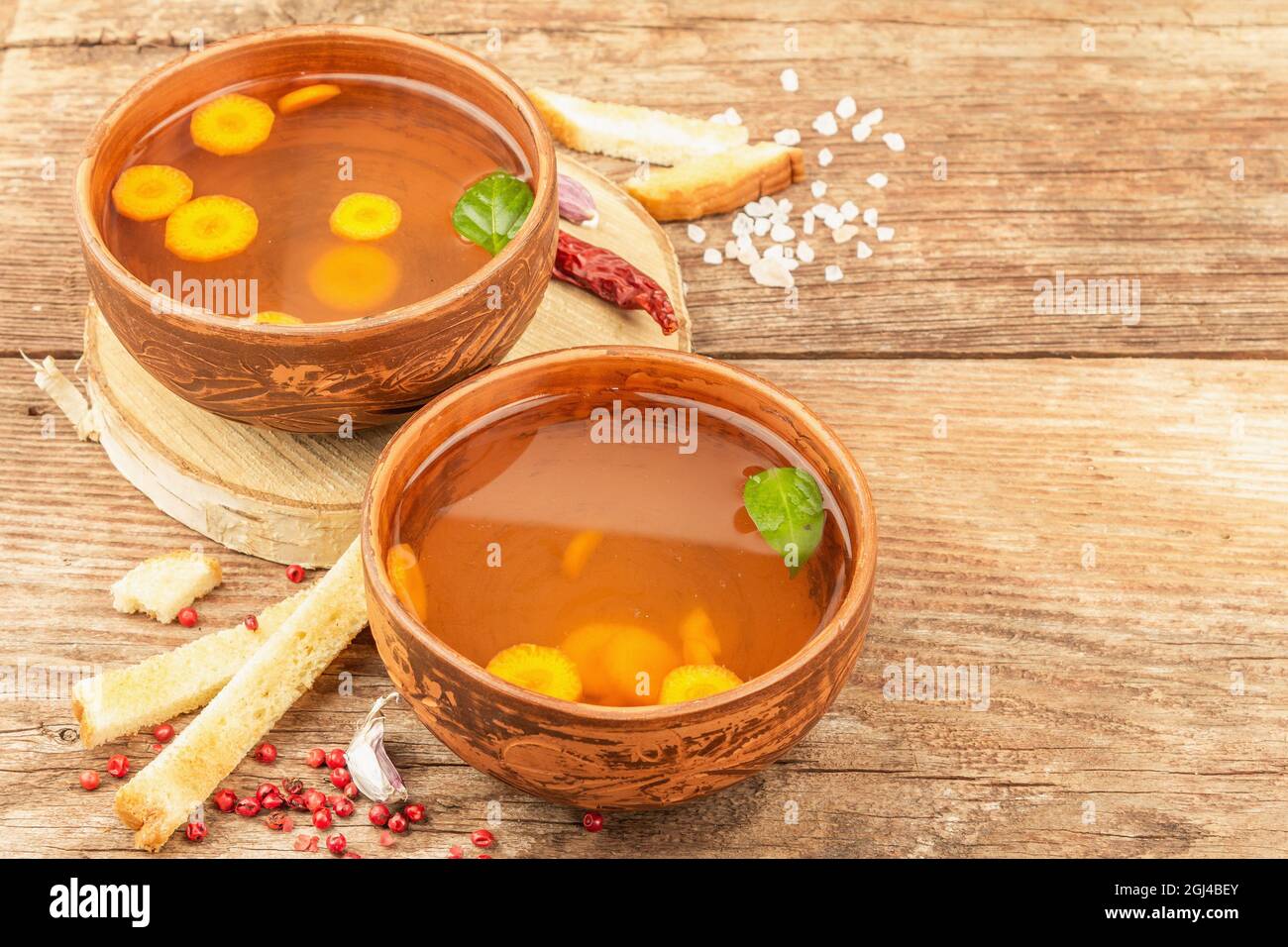 Transparent chicken broth with vegetables in ceramic bowls. Traditional ...