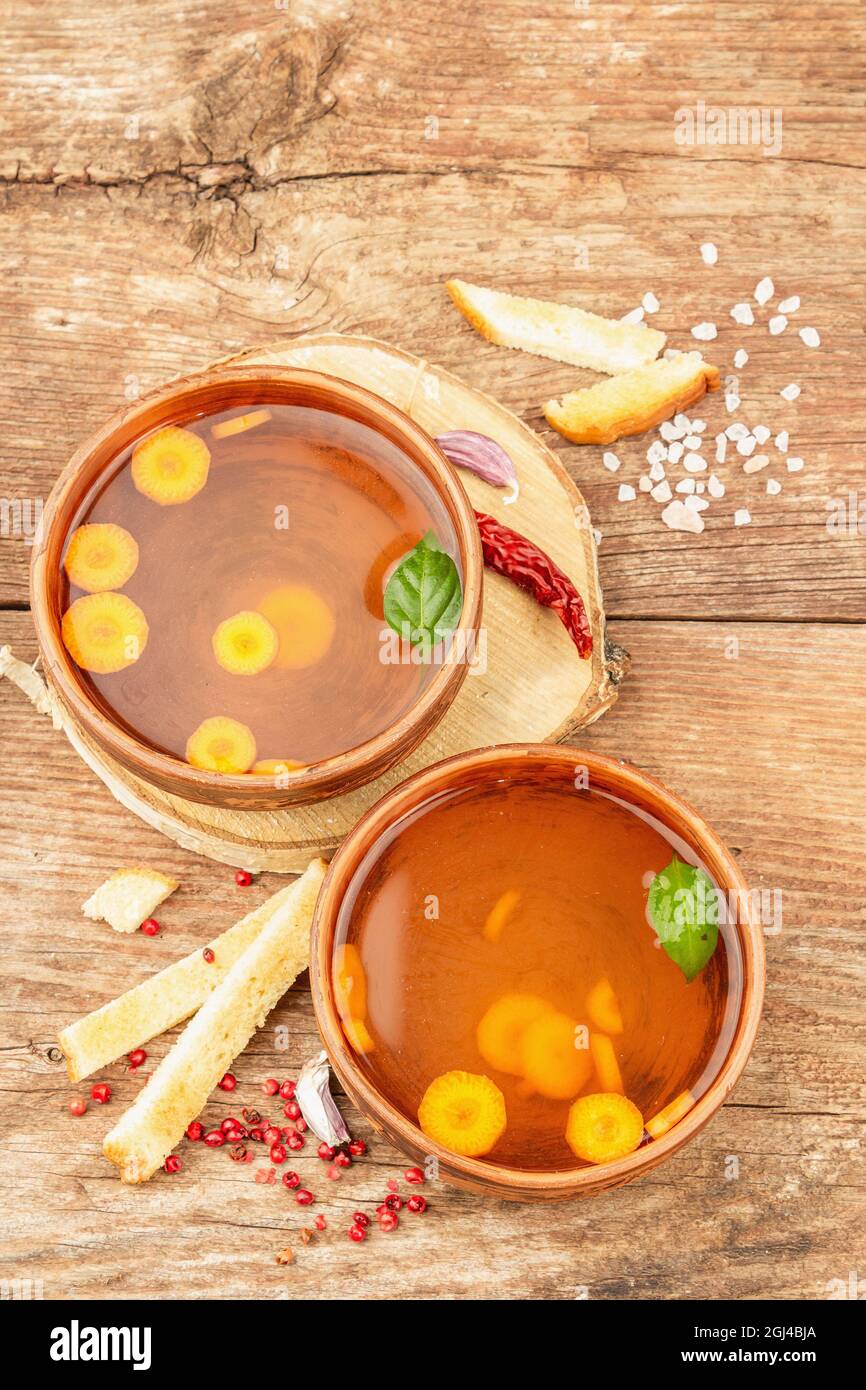 Transparent chicken broth with vegetables in ceramic bowls. Traditional ...