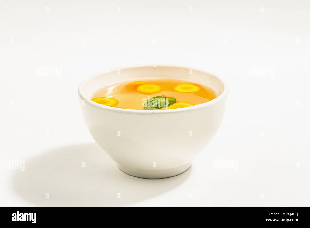 Transparent chicken broth in a ceramic bowl isolated on white ...