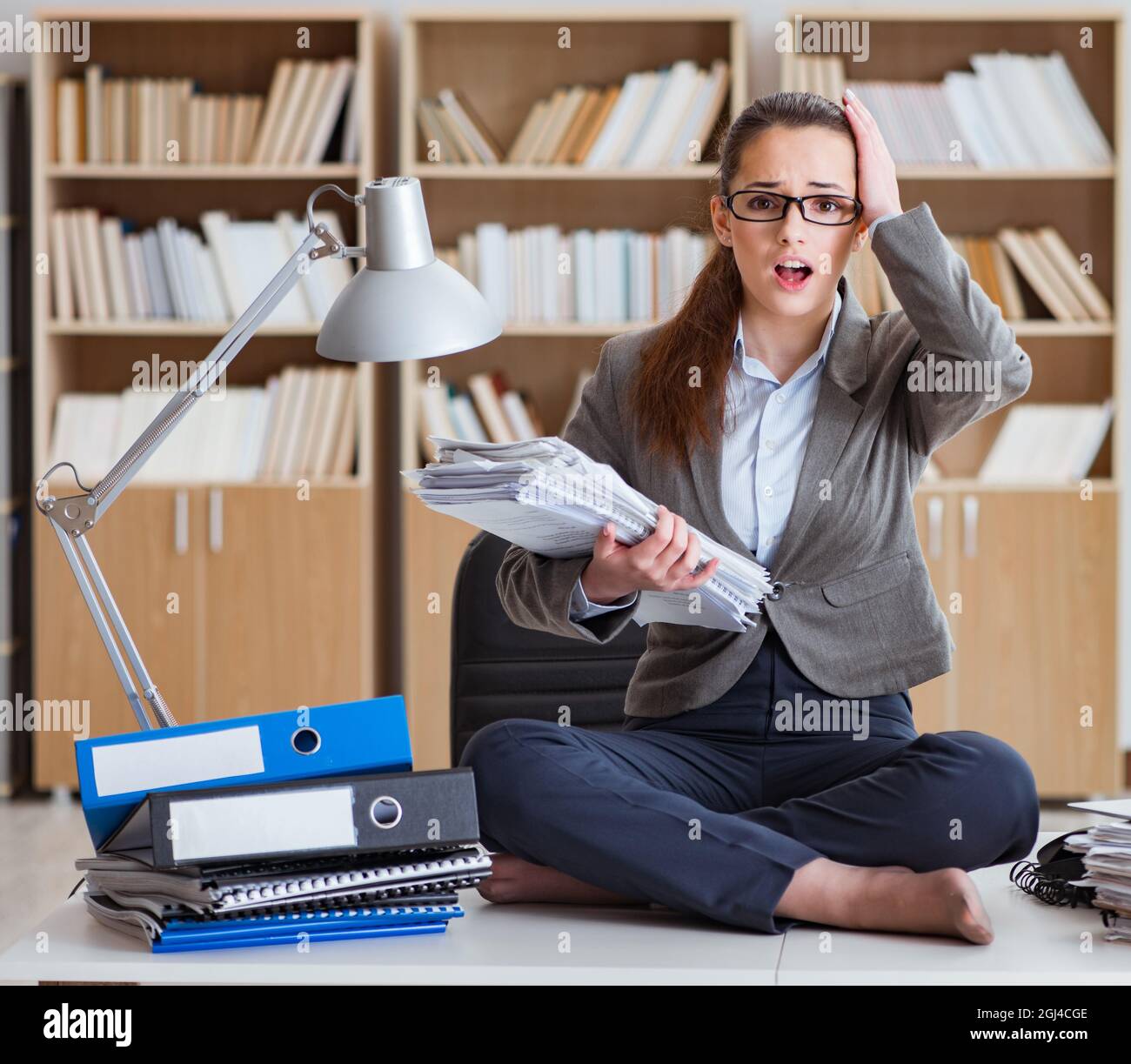 The busy angry businesswoman sitting on the desk in office Stock Photo ...