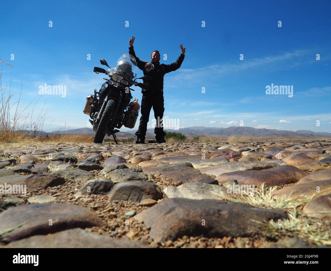 Male motorcyclist with his motorcycle having fun and posing on a desert ...