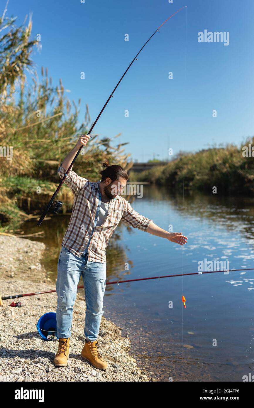 Happy fisherman pulls fish out of the river Stock Photo - Alamy