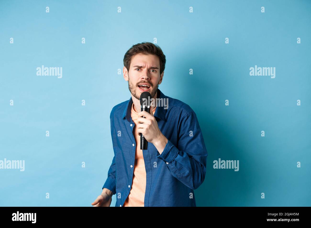 Passionate singer looking at camera, singing in microphone, playing ...