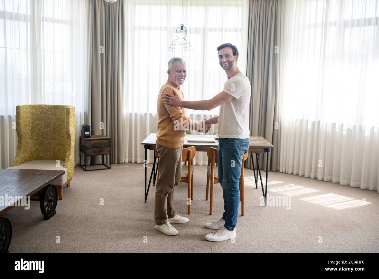 Son visitng his dad, both looking happy Stock Photo - Alamy