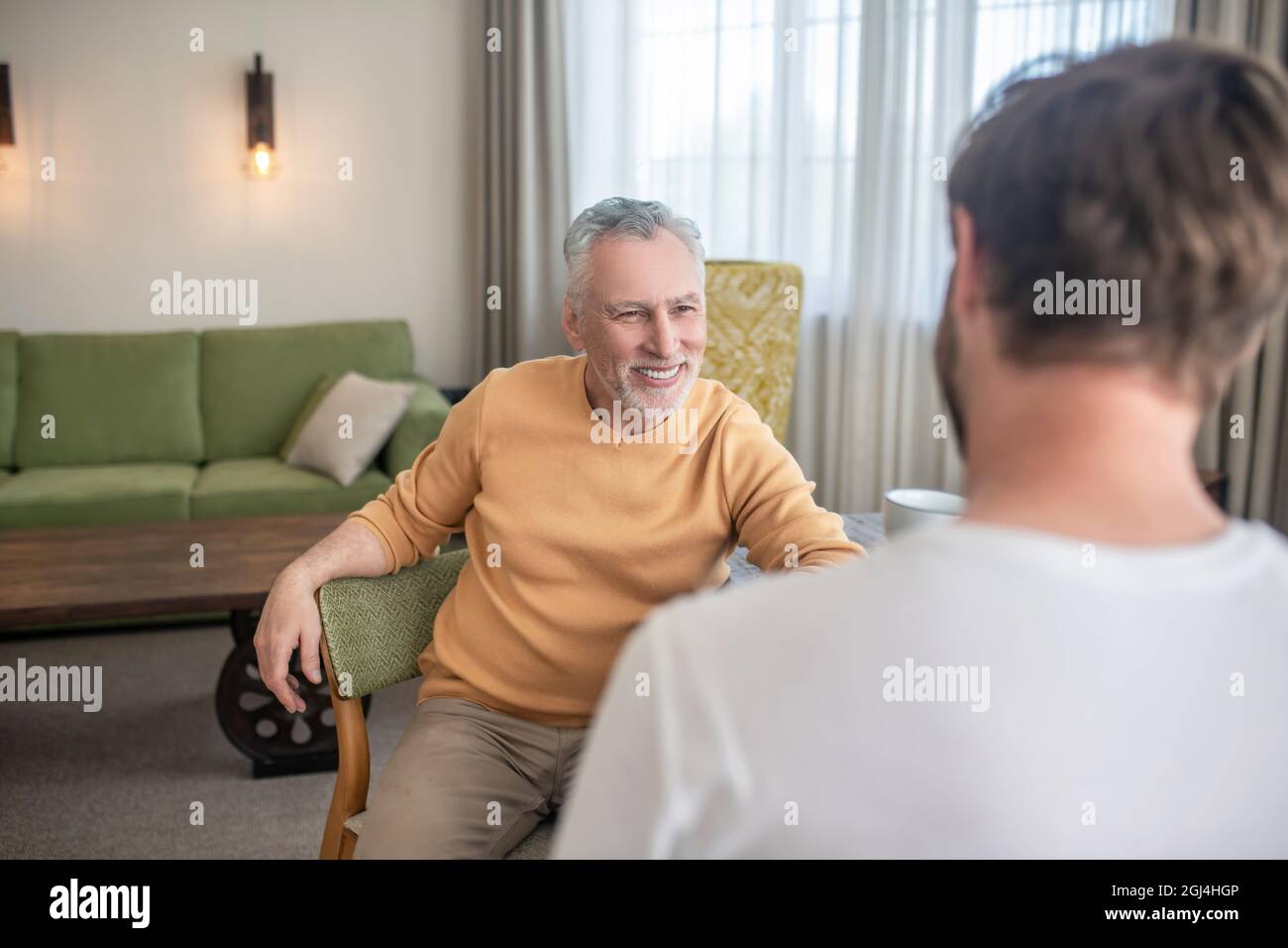 Two men sitting at the table, having tea and talking Stock Photo - Alamy
